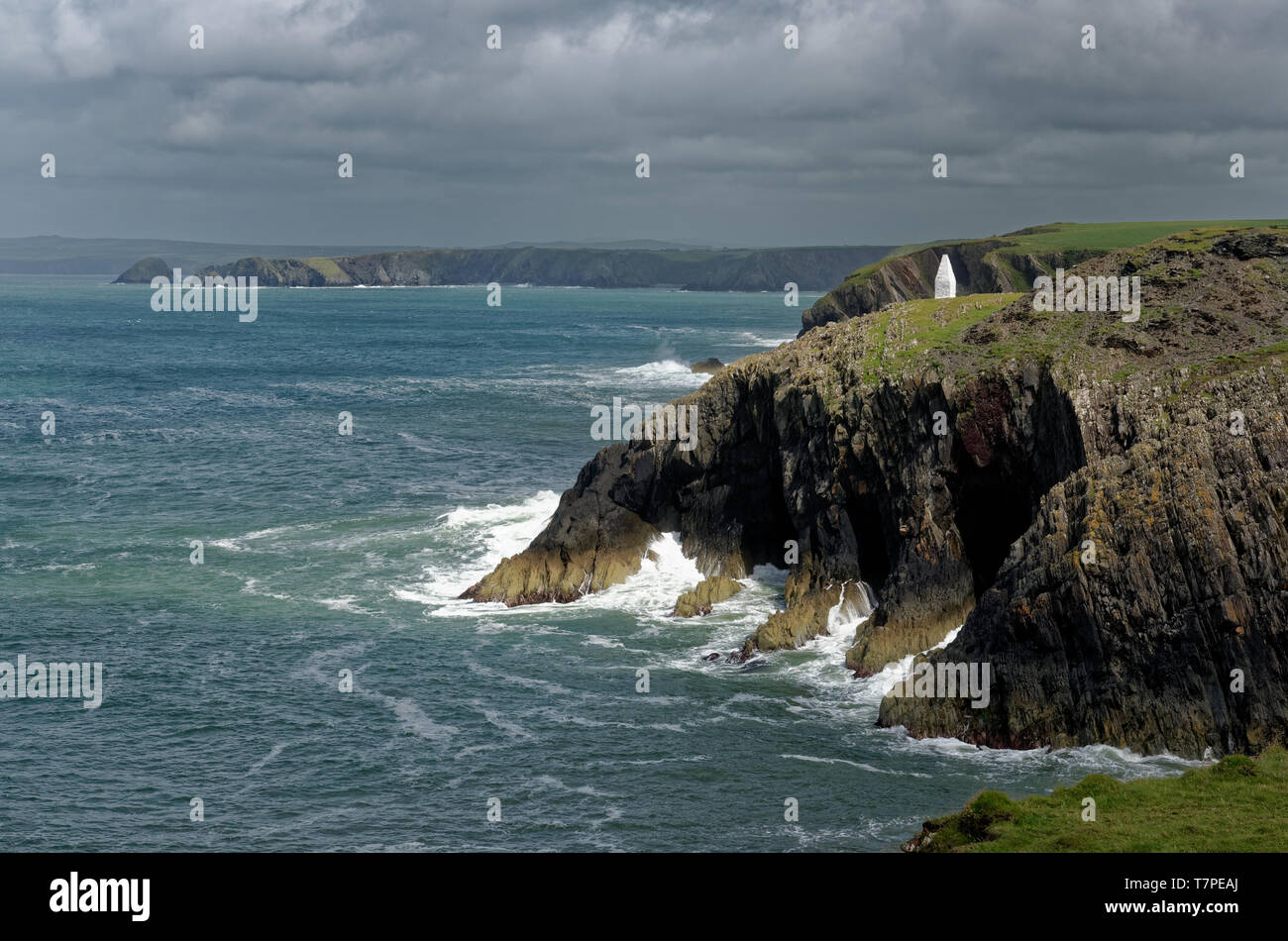 Dramatic cliffs and a white stone navigation marker in the sunlight on ...