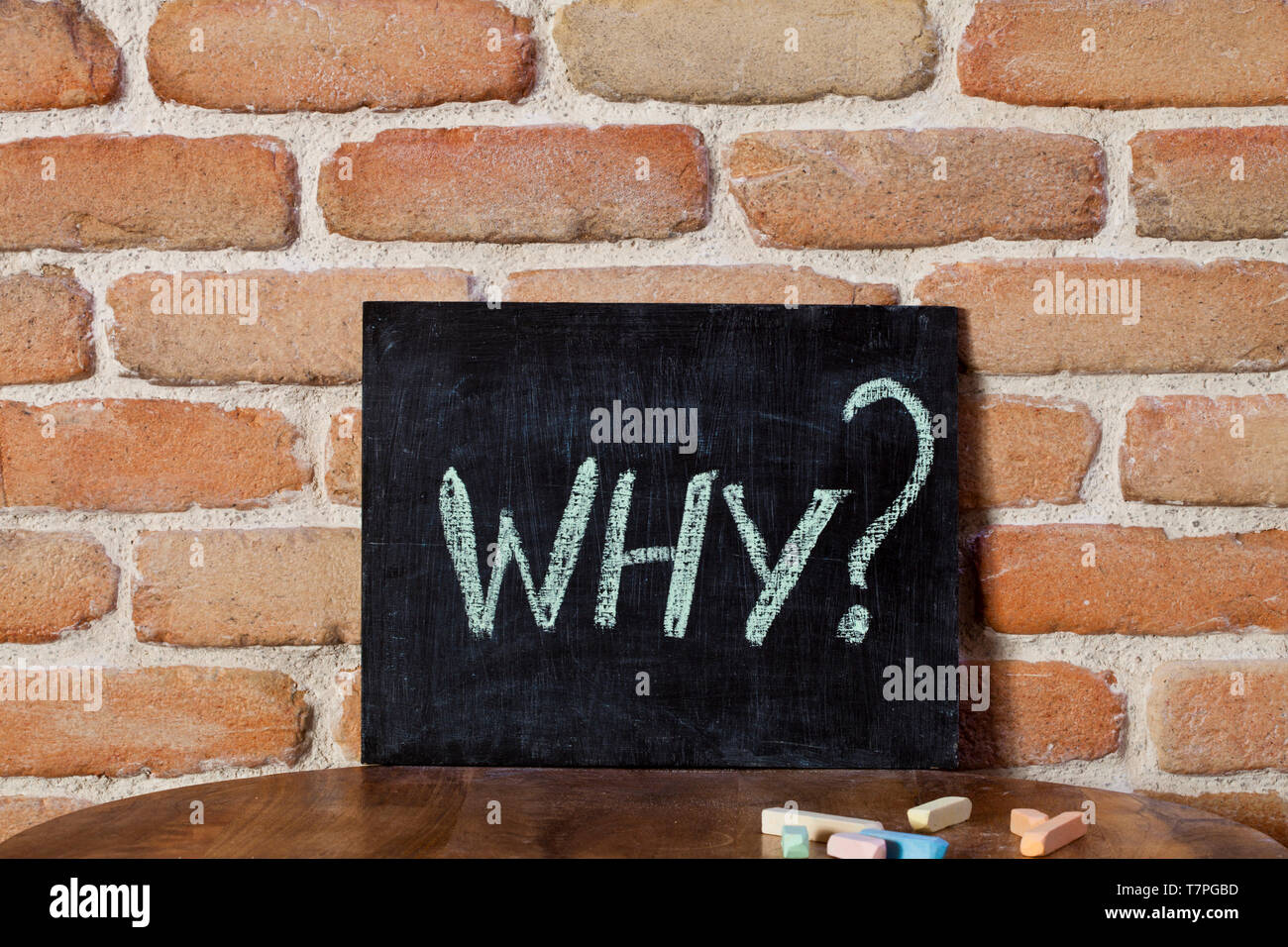 Black board with the word WHY? drown by hand on wooden table on brick ...