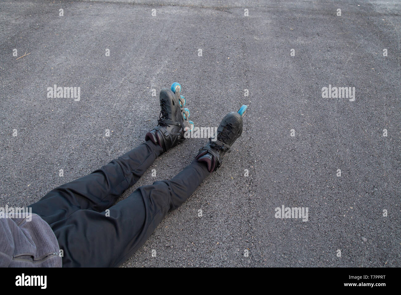 Crop from above young tired fit man in sportswear with roller skates ...