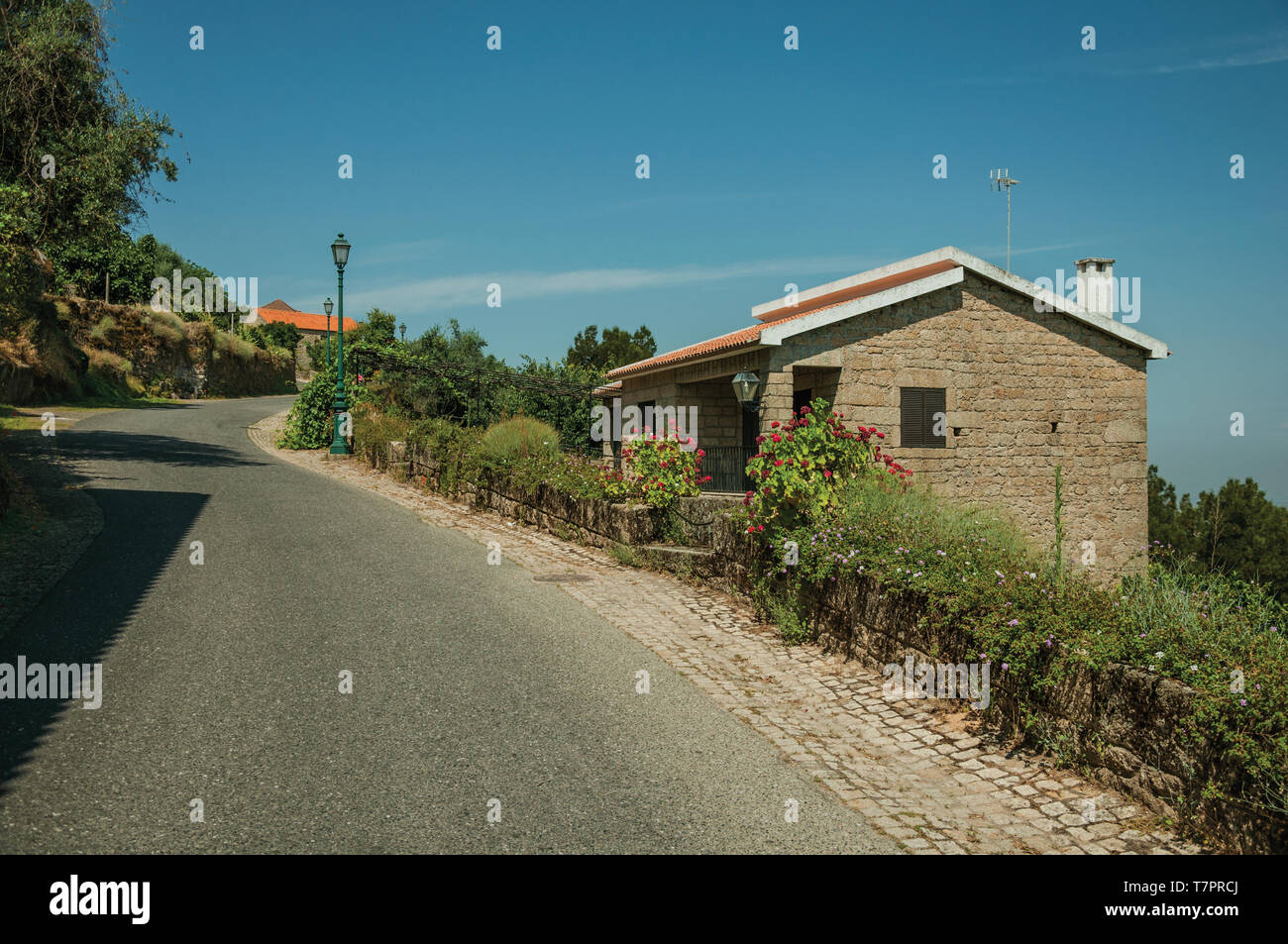 Road on slope with stone parapet and rustic house, on hilly landscape ...