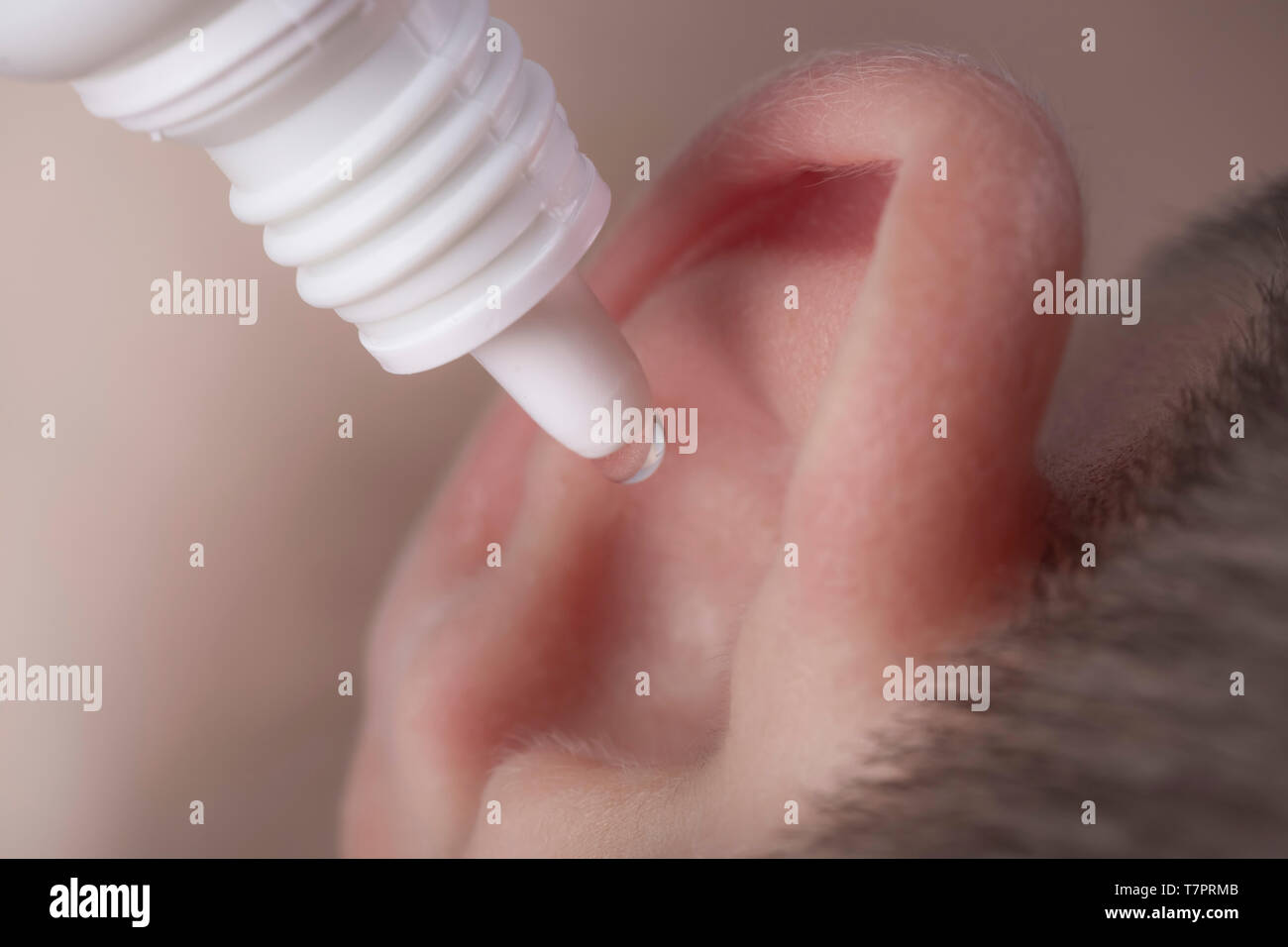 Medical pipette with a drop of medication over the patient's ear. Ear ...