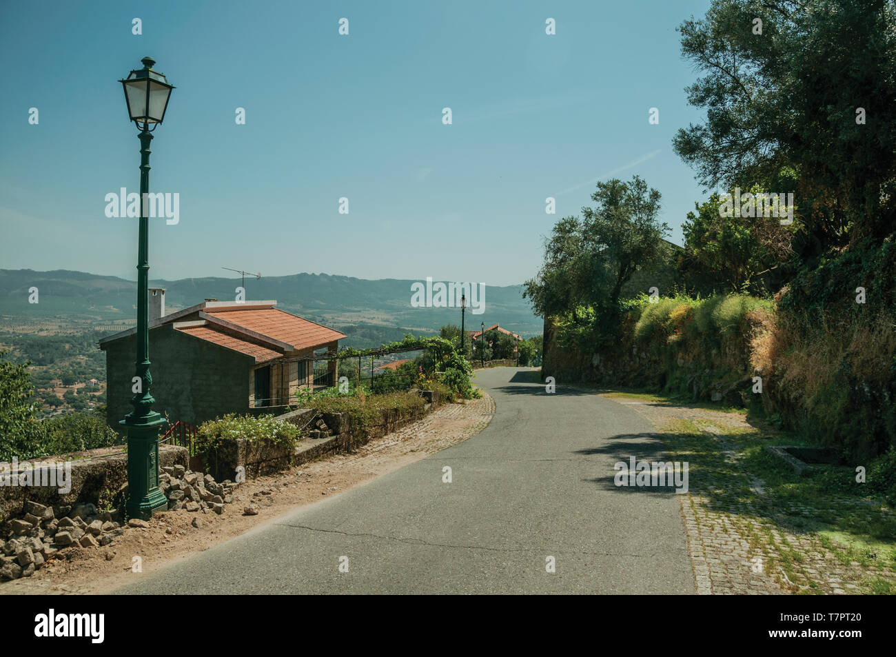 Road on slope with stone parapet and rustic house, on hilly landscape ...