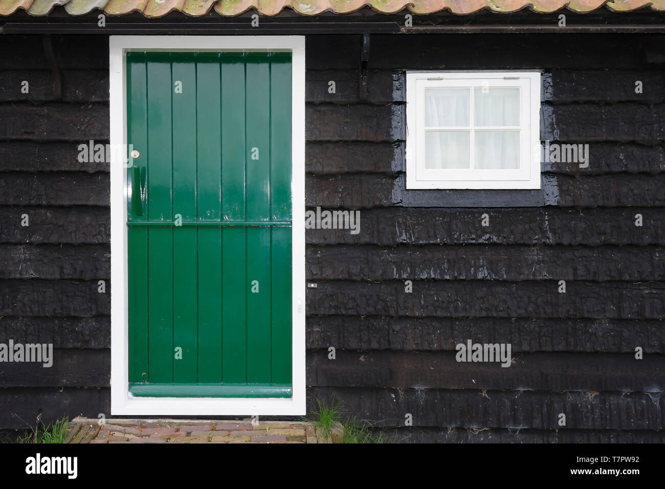 Front door of small rural cottage house with wooden wall and green door ...