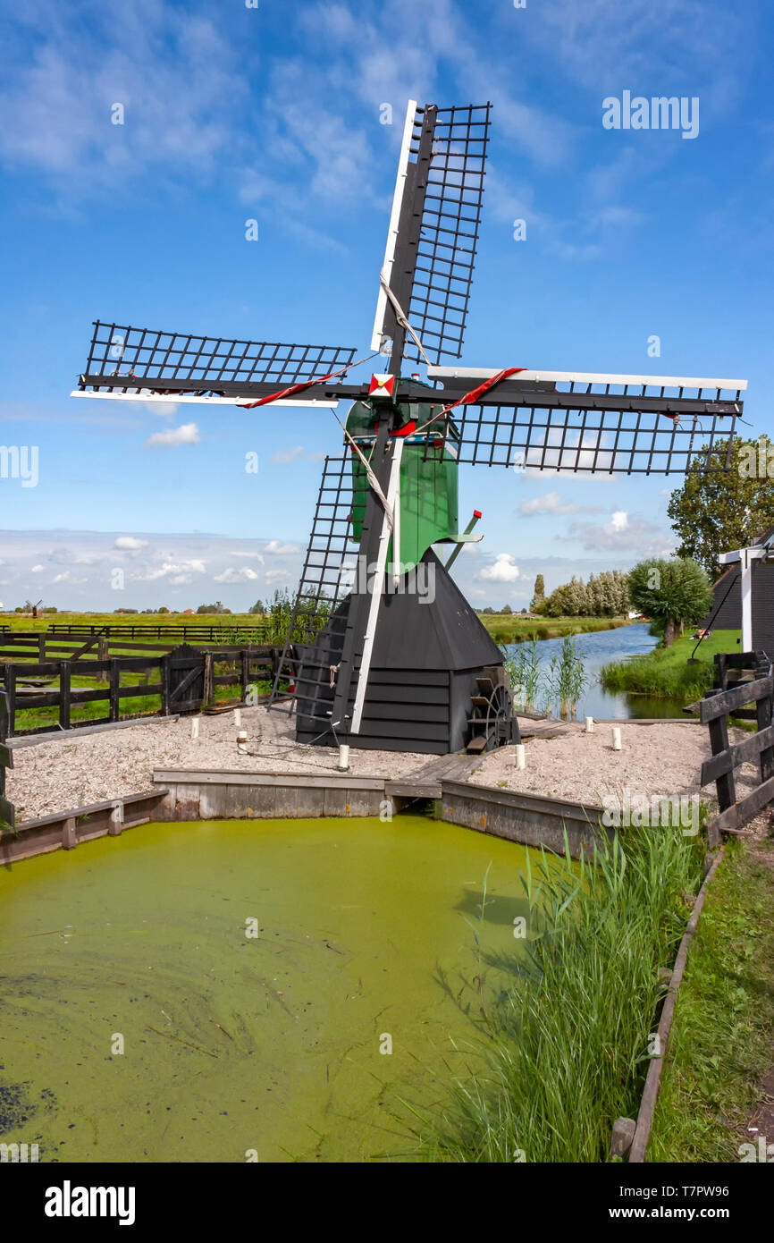 Small Dutch personal green windmill in the middle of a small canal ...