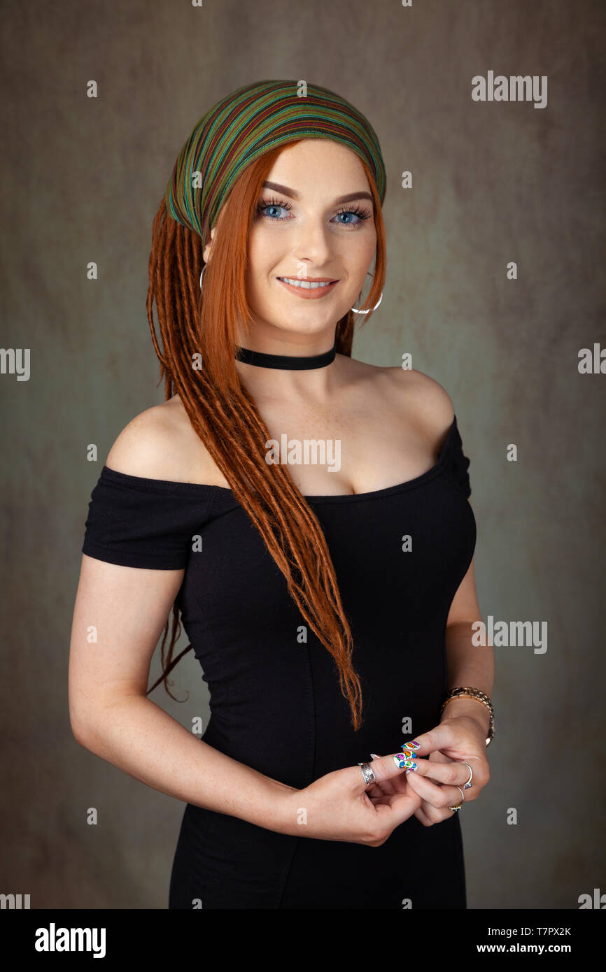 Portrait pf a beautiful red headed woman with dreadlocks and wearing a ...