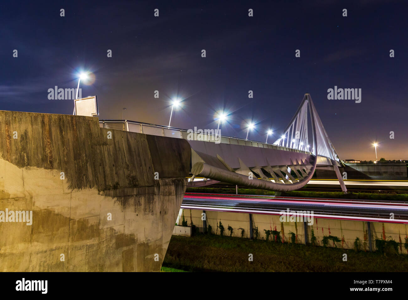 Suspension bridge at night under moonlight with light trails of moving ...