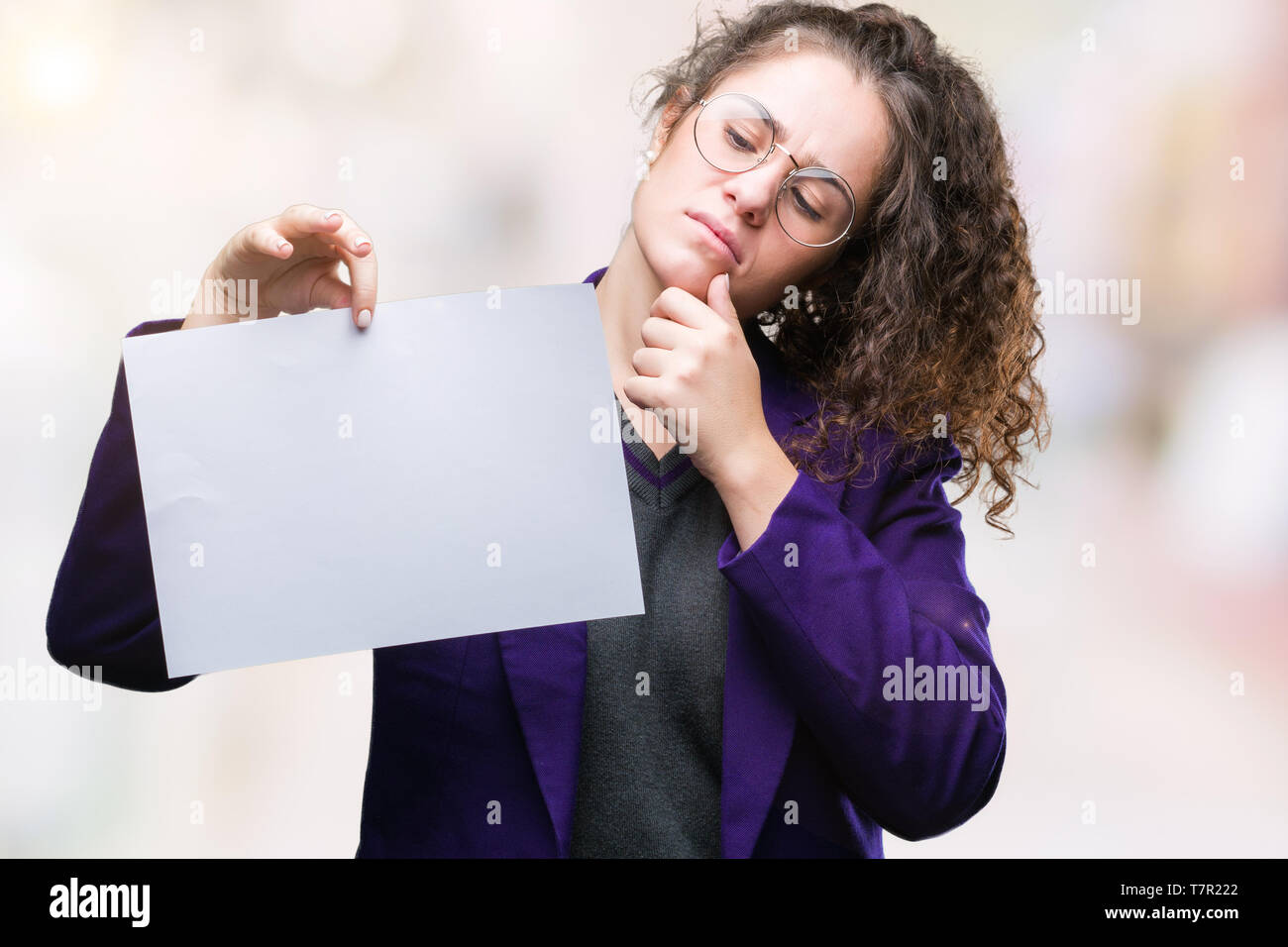Young brunette student girl wearing school uniform holding blank paper ...