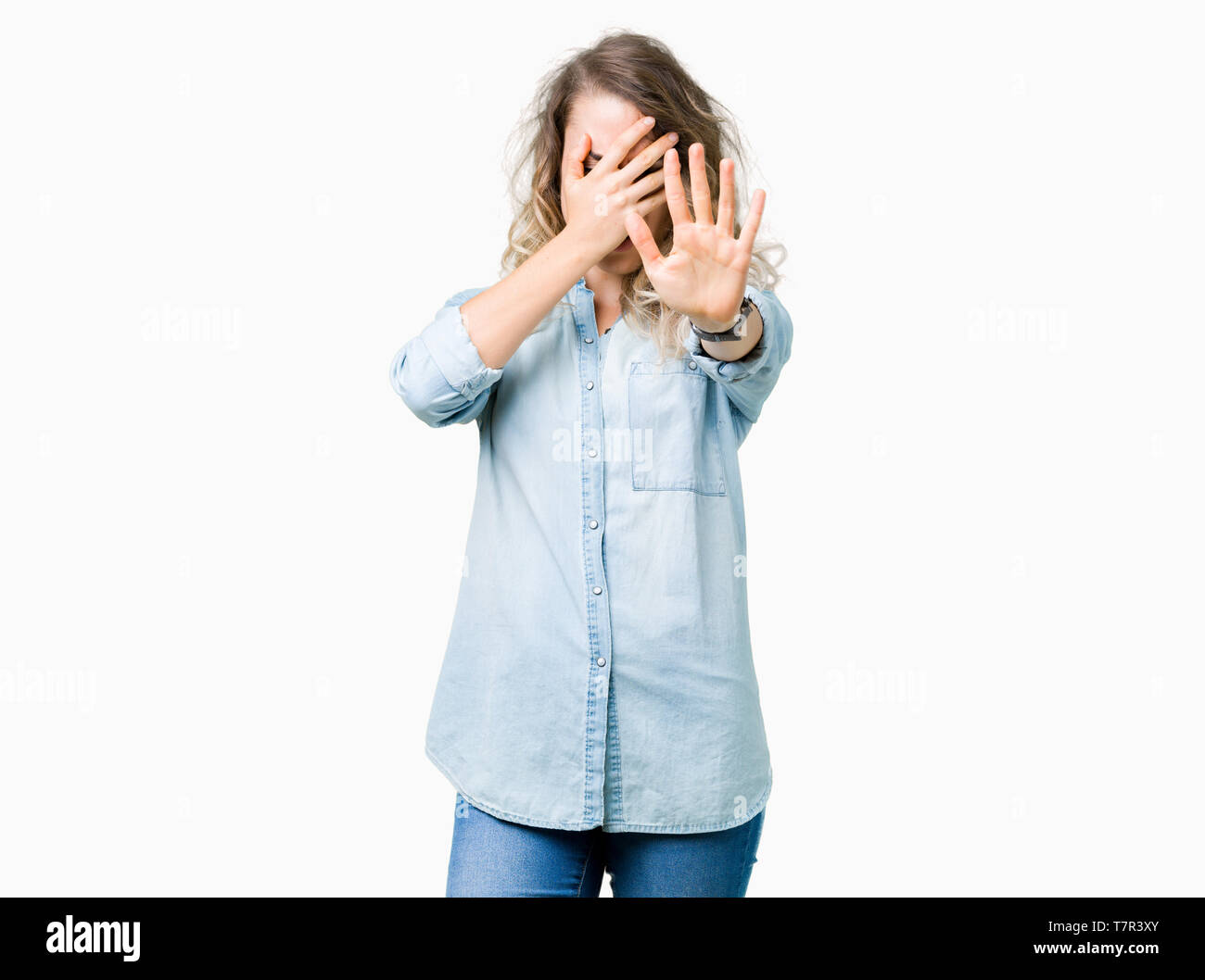 Beautiful young blonde woman over isolated background covering eyes ...