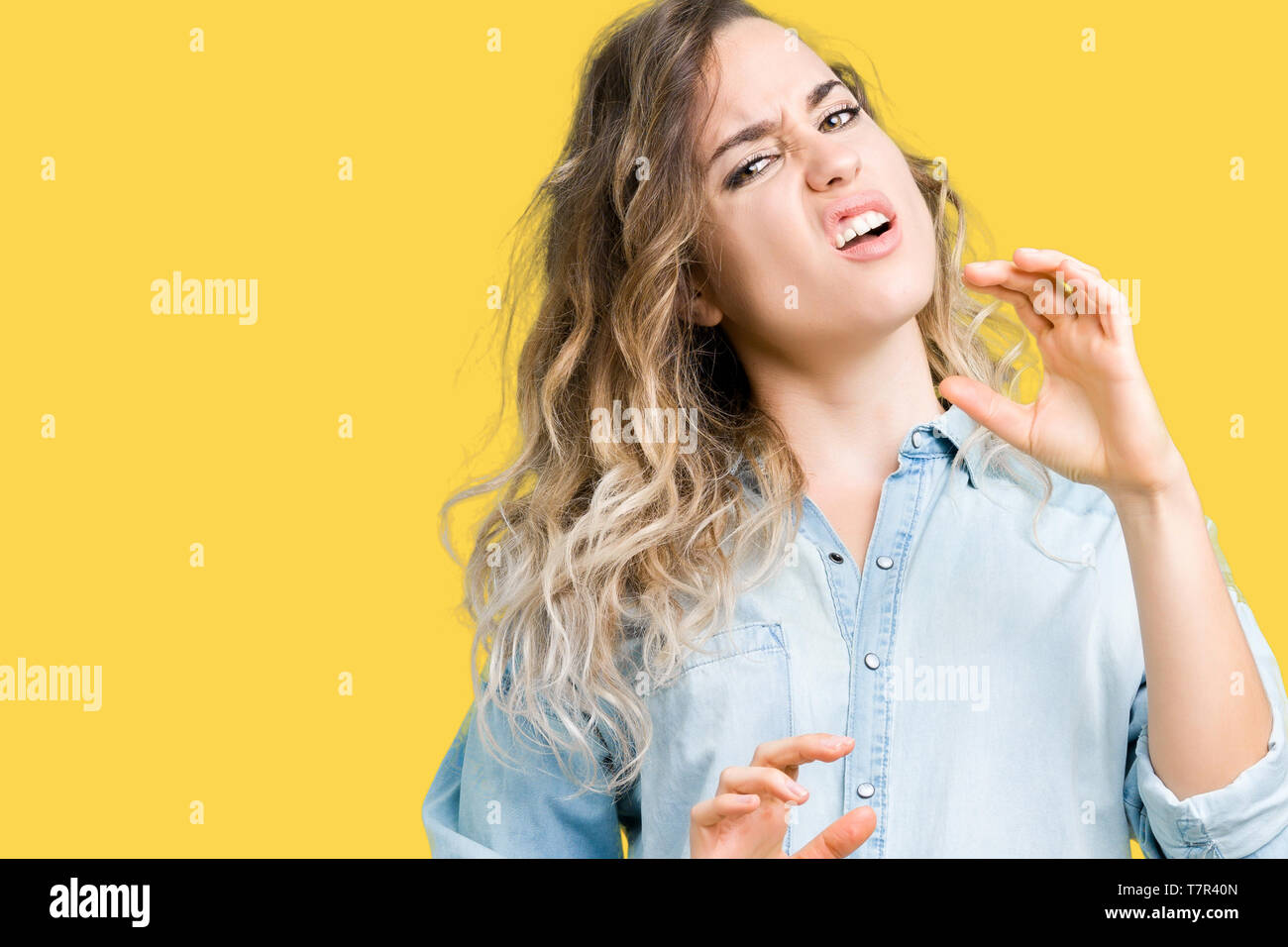 Beautiful young blonde woman over isolated background disgusted expression, displeased and ...