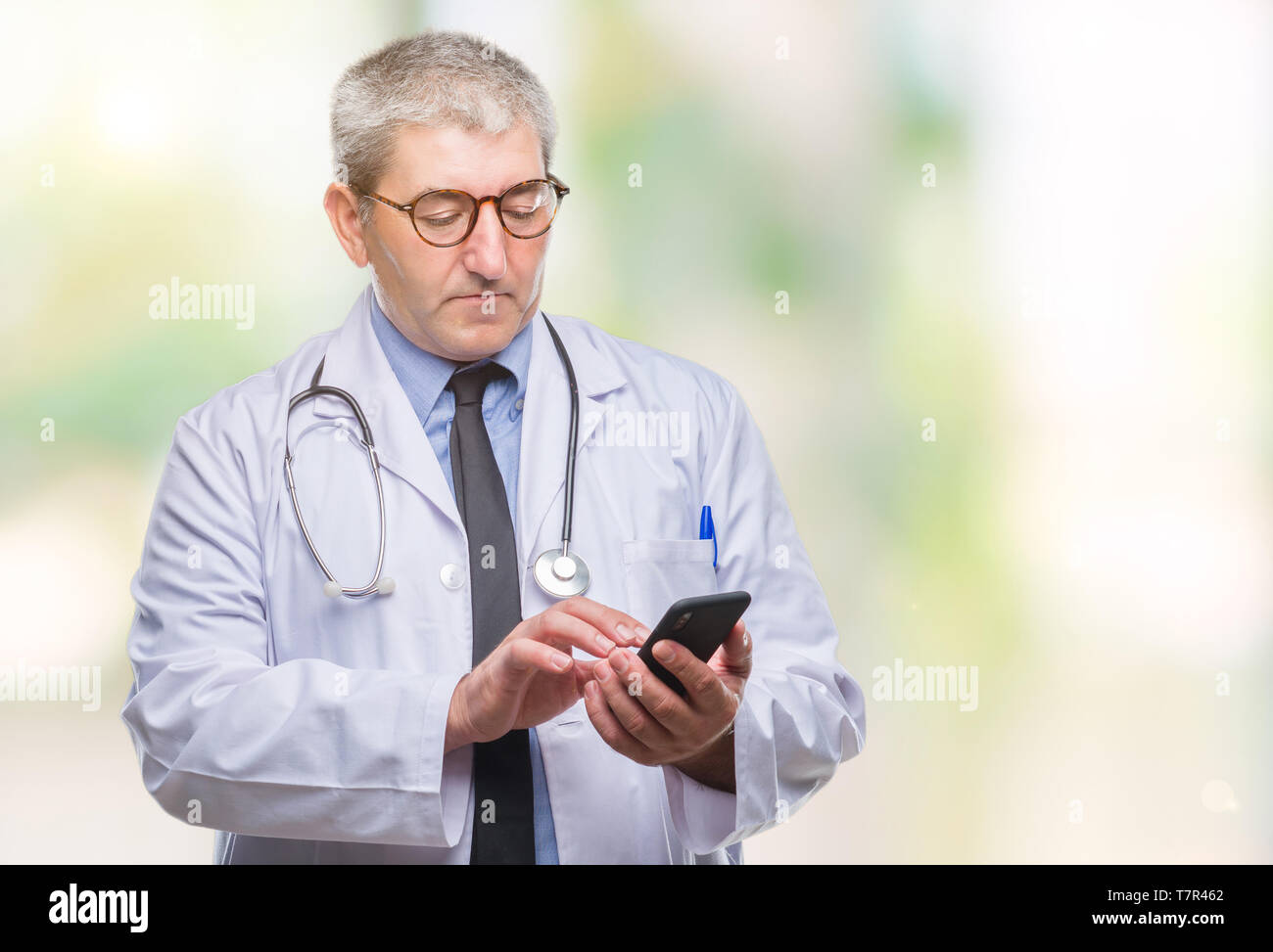 Handsome senior doctor man texting sending message using smarpthone ...