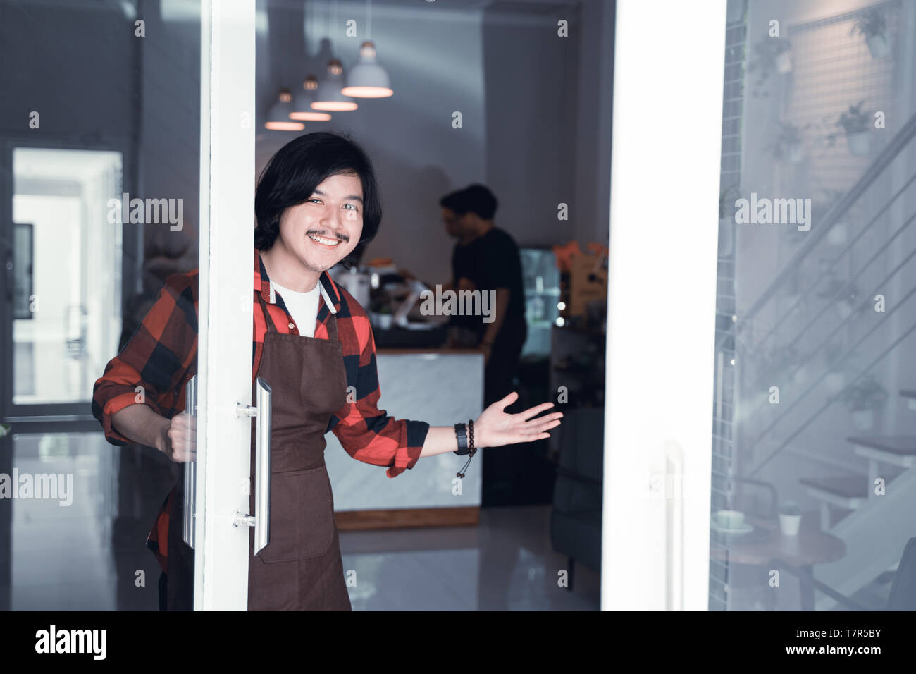 barista open the door in his cafe welcoming Stock Photo - Alamy