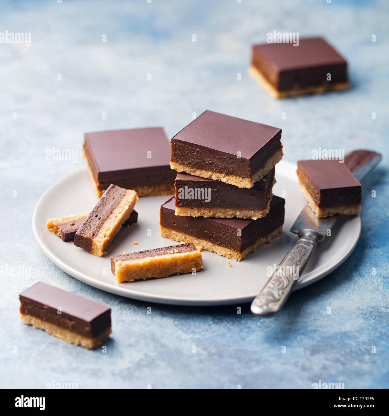 Chocolate caramel slices, bars, millionaires shortbread on a grey plate ...