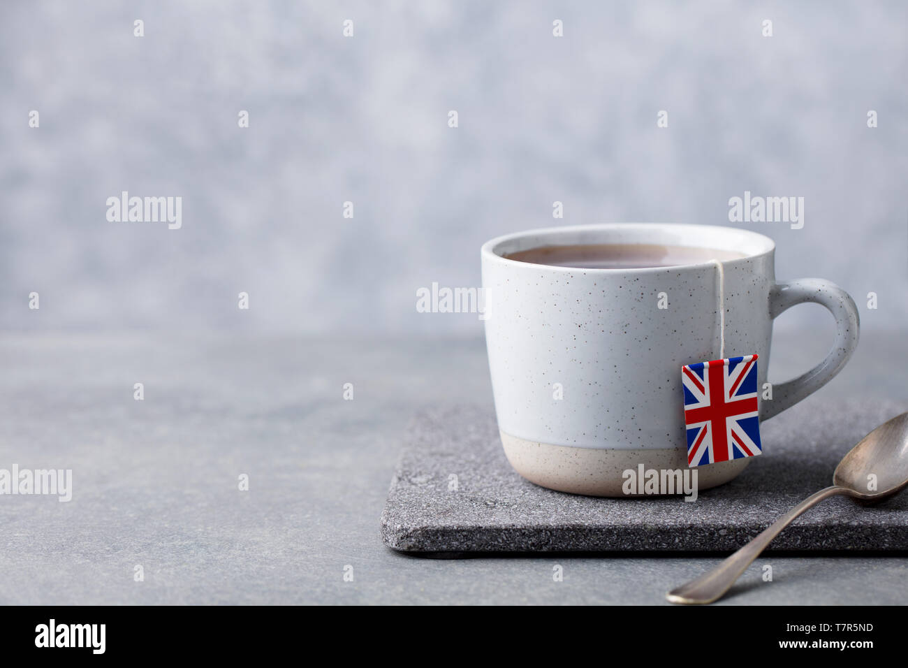 Tea in mug with British flag tea bag label. Grey background. Copy space ...
