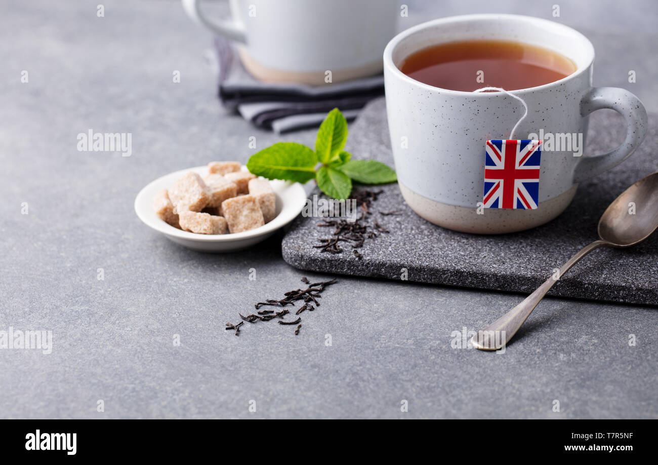Tea in mugs with British flag tea bag label. Grey background. Copy ...