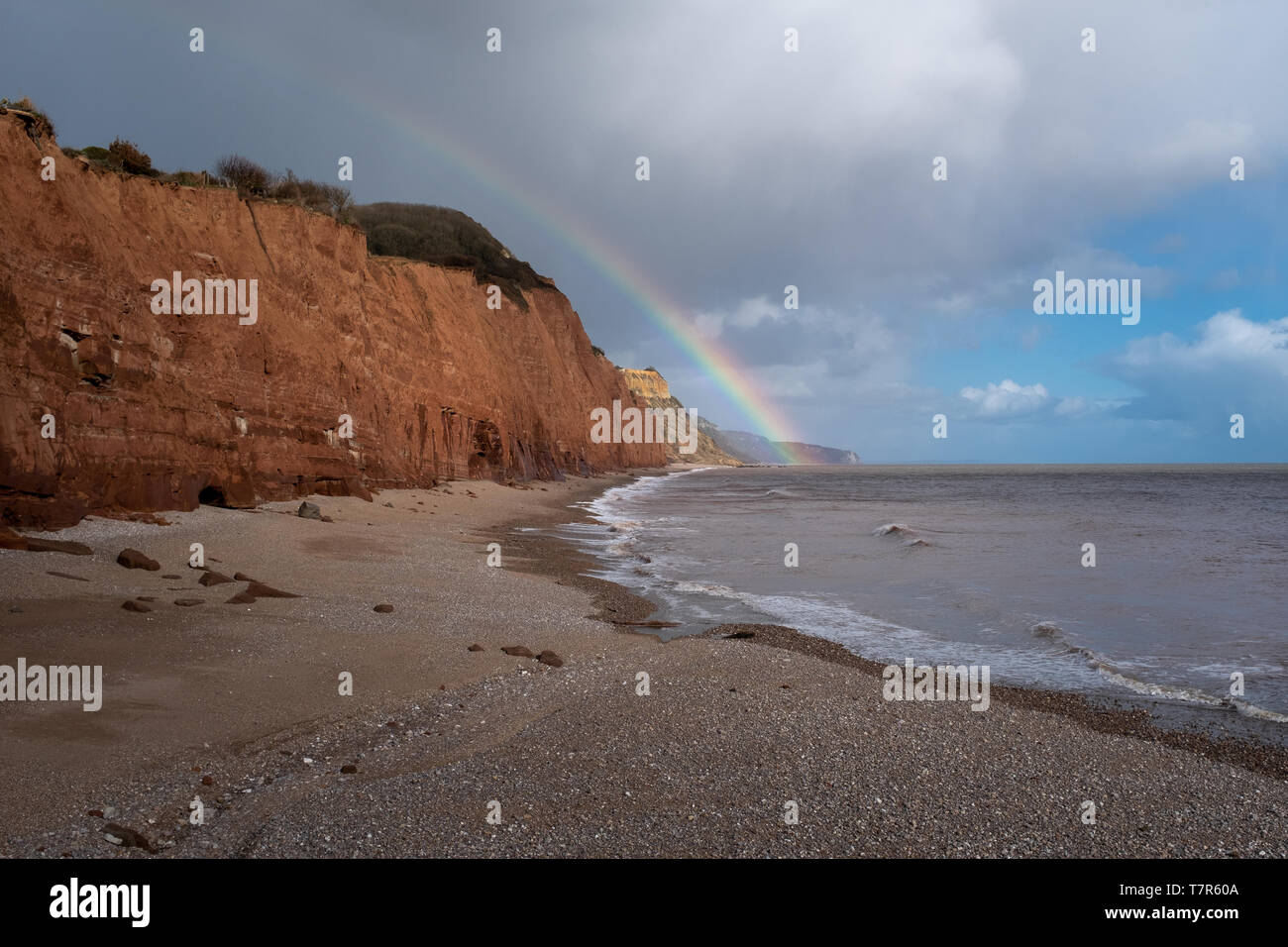 A rainbow touches down on a deserted Sidmouth beach in Devon, England ...