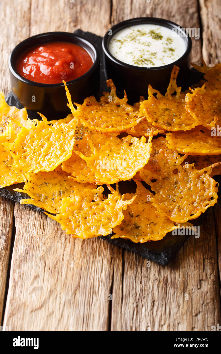 Fried cheddar cheese chips with herbs served with sauces close-up on ...