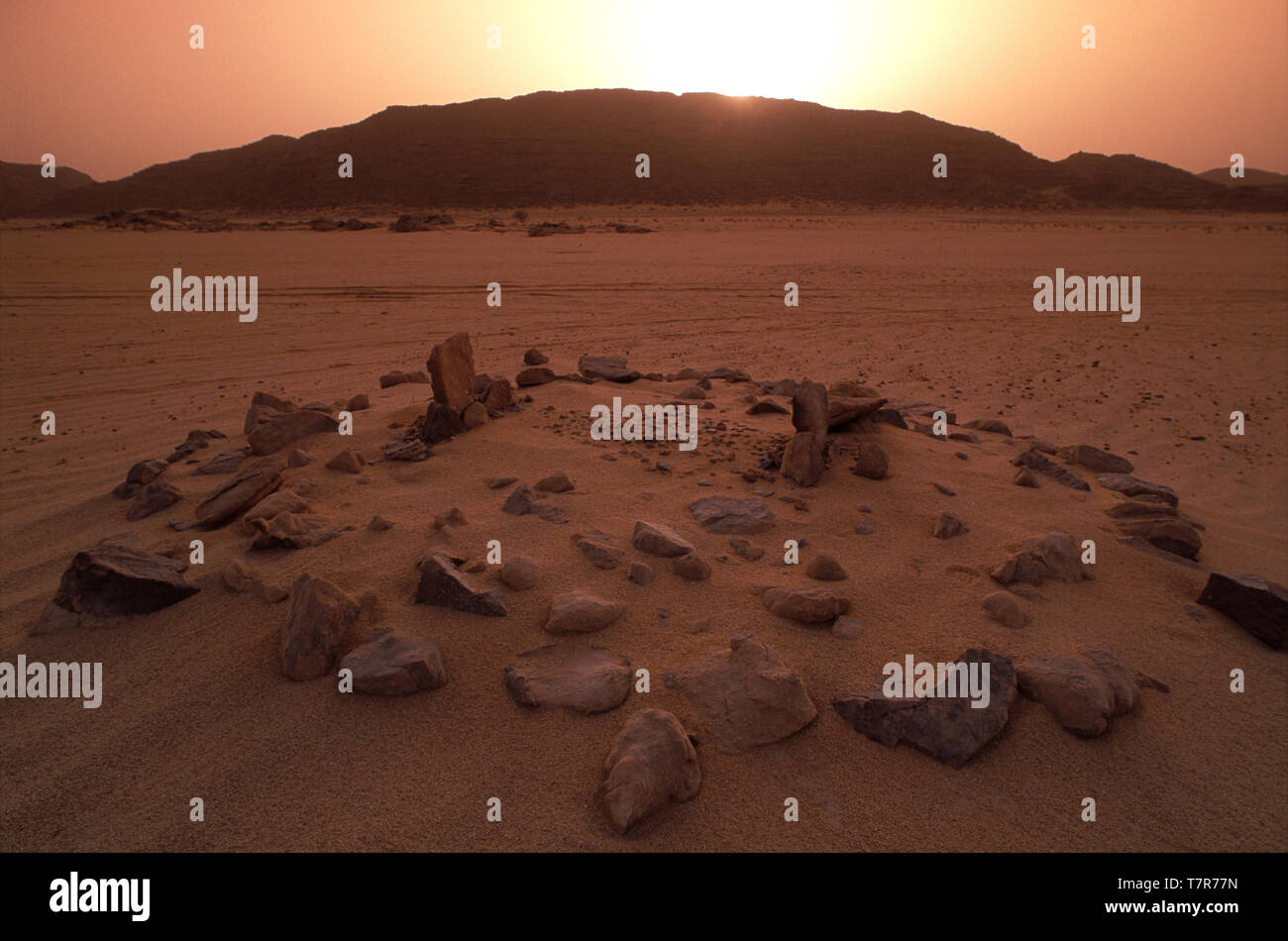An old primitive grave with a sunset in the Sahara desert in Algeria ...