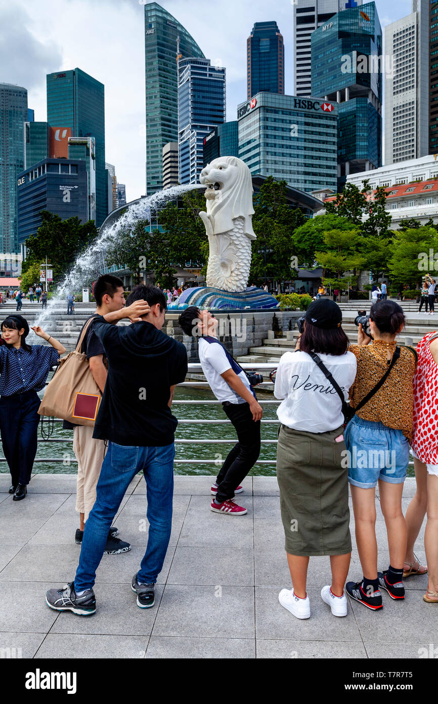 Tourists Pose For Photos In Front Of The Merlion Statue and Singapore ...