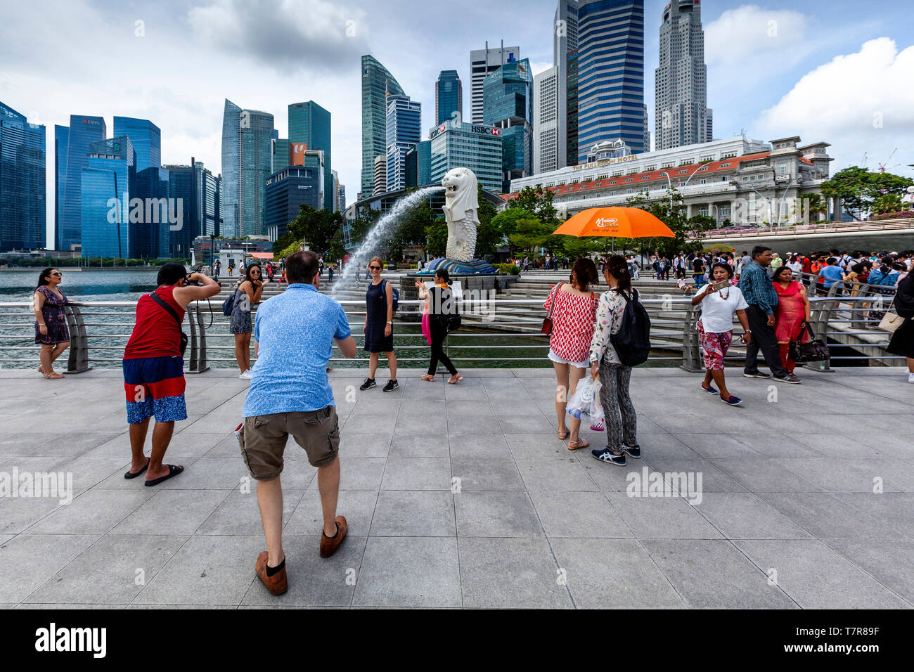 Tourists Pose For Photos In Front Of The Merlion Statue and Singapore ...