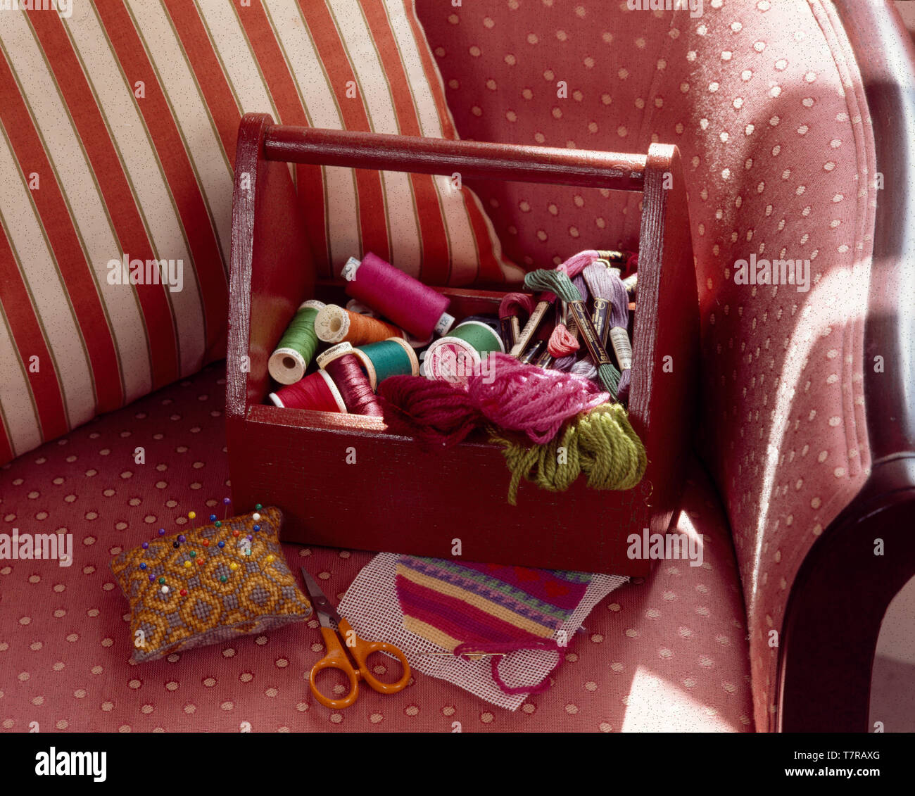 Reels of cotton in wooden sewing tidy on pink chair Stock Photo - Alamy