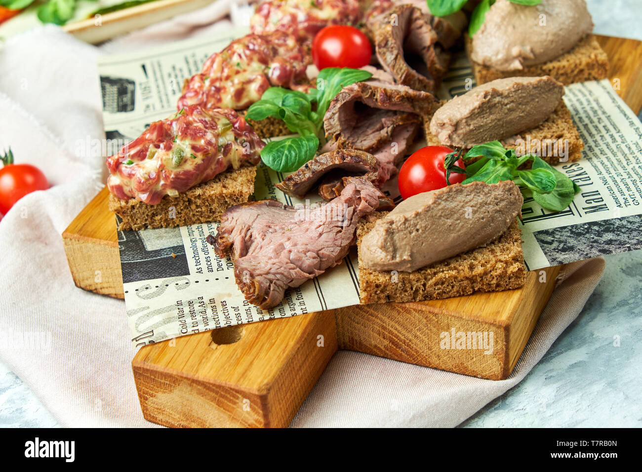 Cold meat snacks on a wooden board. Beautiful serving dishes. Light ...