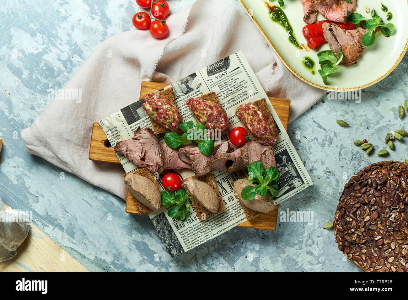 Cold meat snacks on a wooden board. Beautiful serving dishes. Light ...