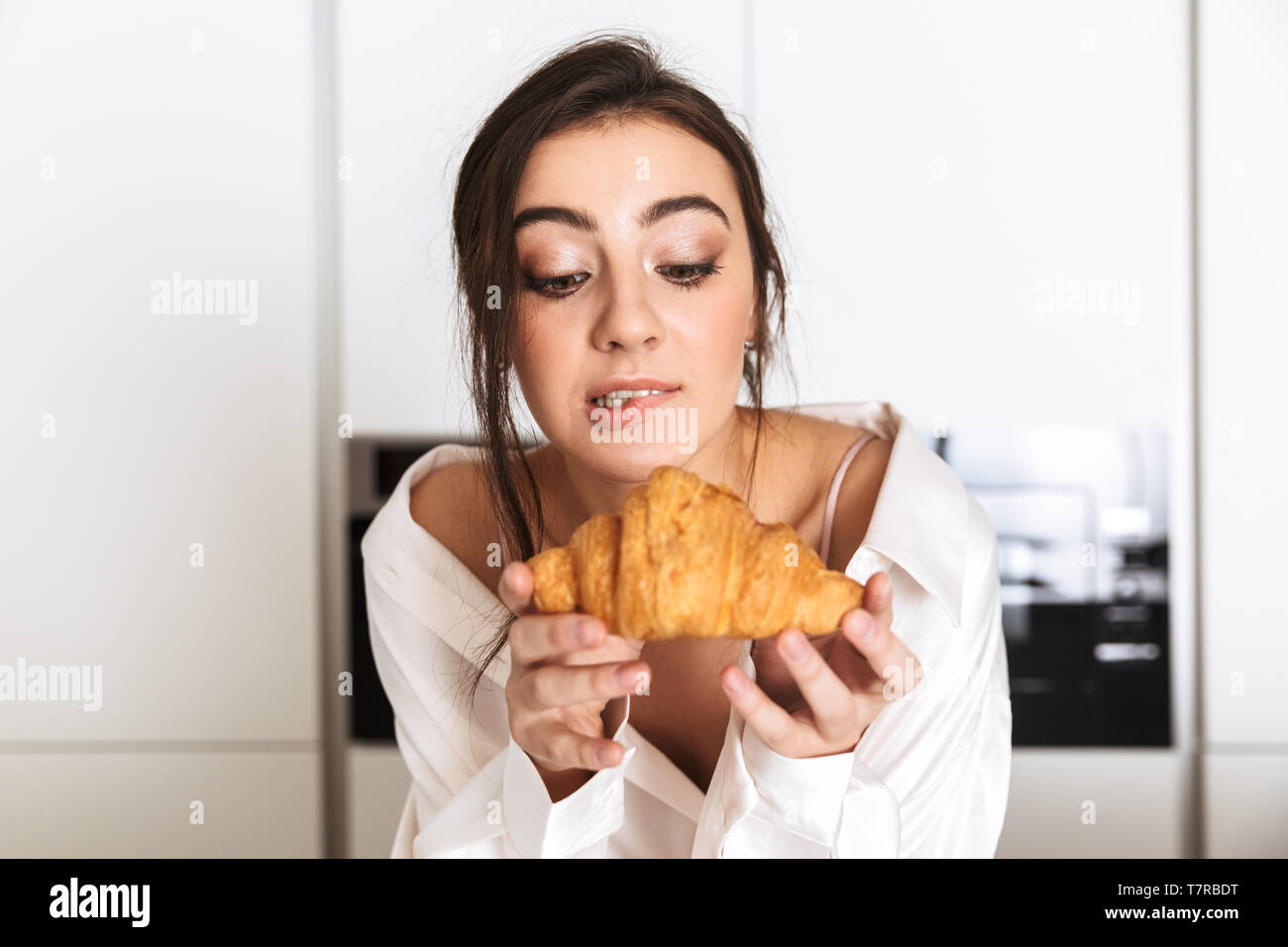 Photo of beautiful woman 20s wearing silk leisure clothing eating ...