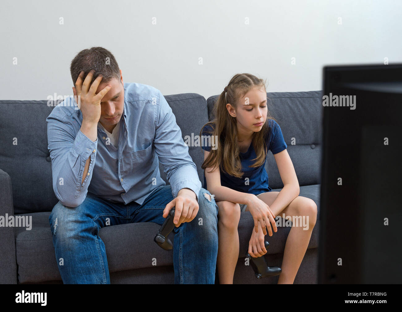 Upset father and daughter sitting on the sofa with gamepads Stock Photo ...
