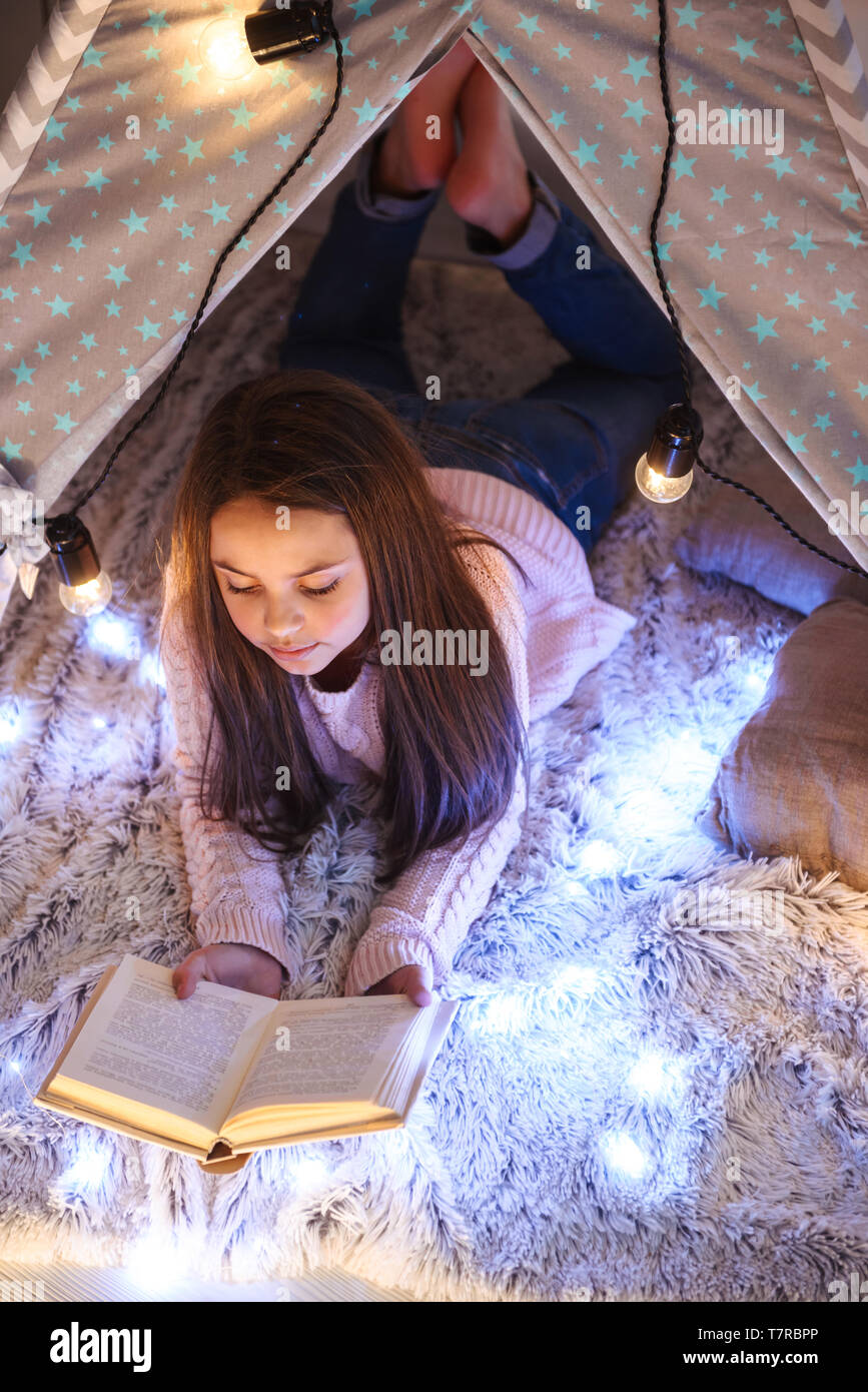 Cute little girl playing at the childrens tent at the bedroom, reading ...