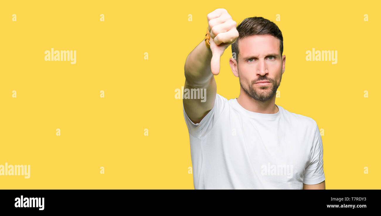 Handsome man wearing casual white t-shirt looking unhappy and angry ...