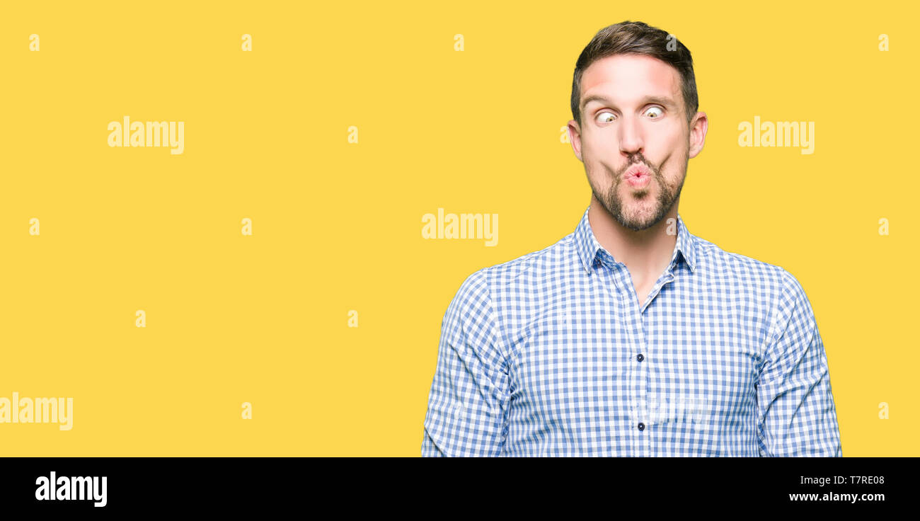 Handsome business man with blue eyes making fish face with lips, crazy ...