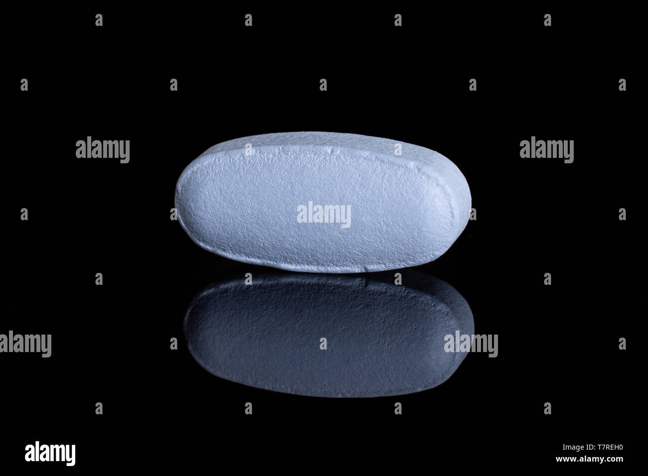One whole blue medical drug isolated on black glass Stock Photo - Alamy