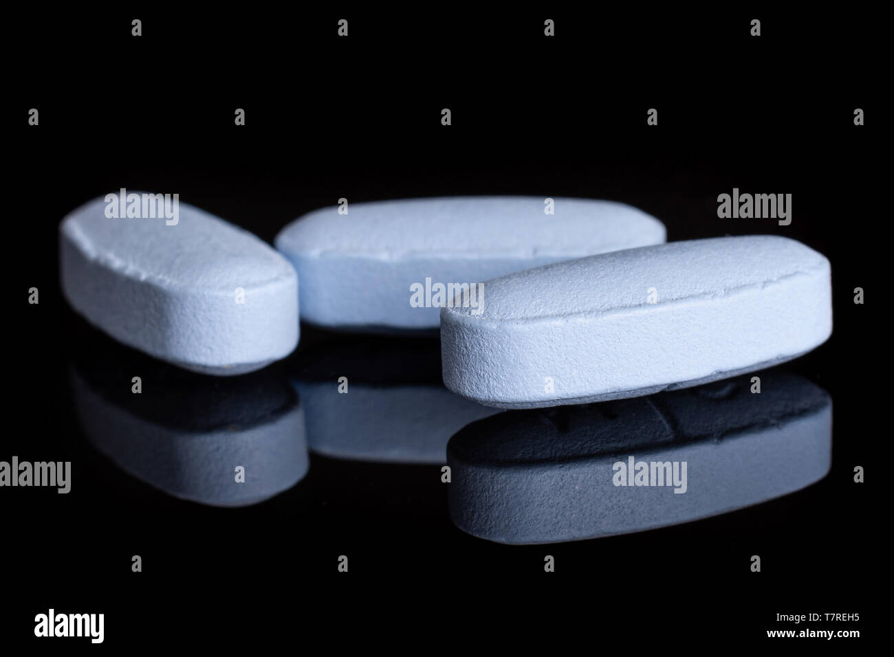 Group of three whole blue medical drug isolated on black glass Stock ...