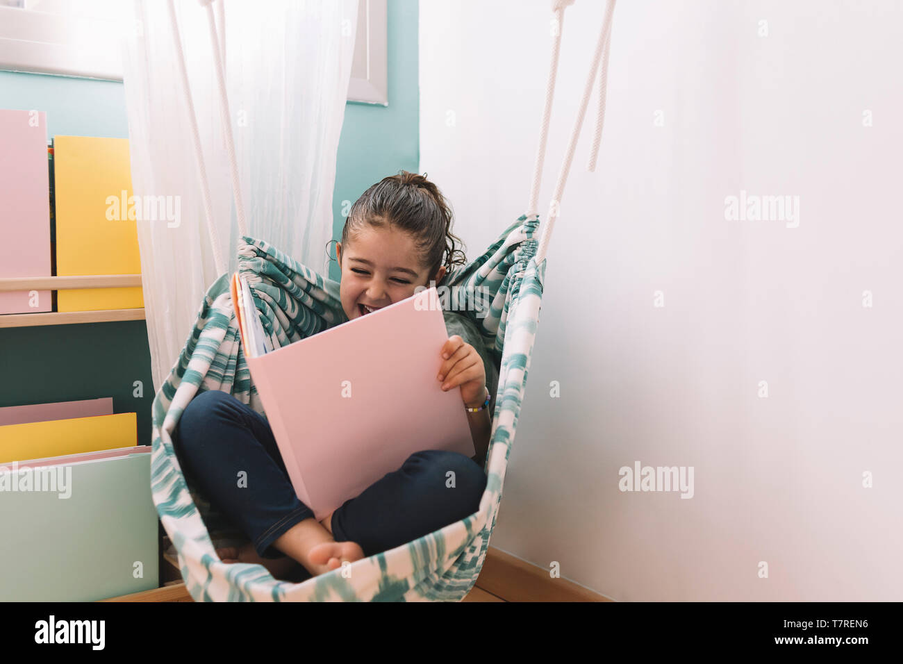 little girl laughing while reading a book in her kids room near the ...