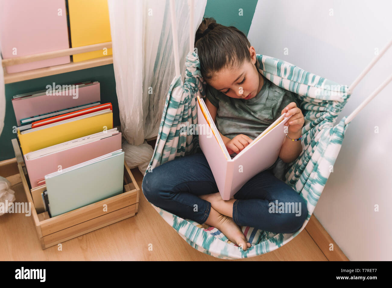 little girl concentrated reading a book in her kids room near the ...
