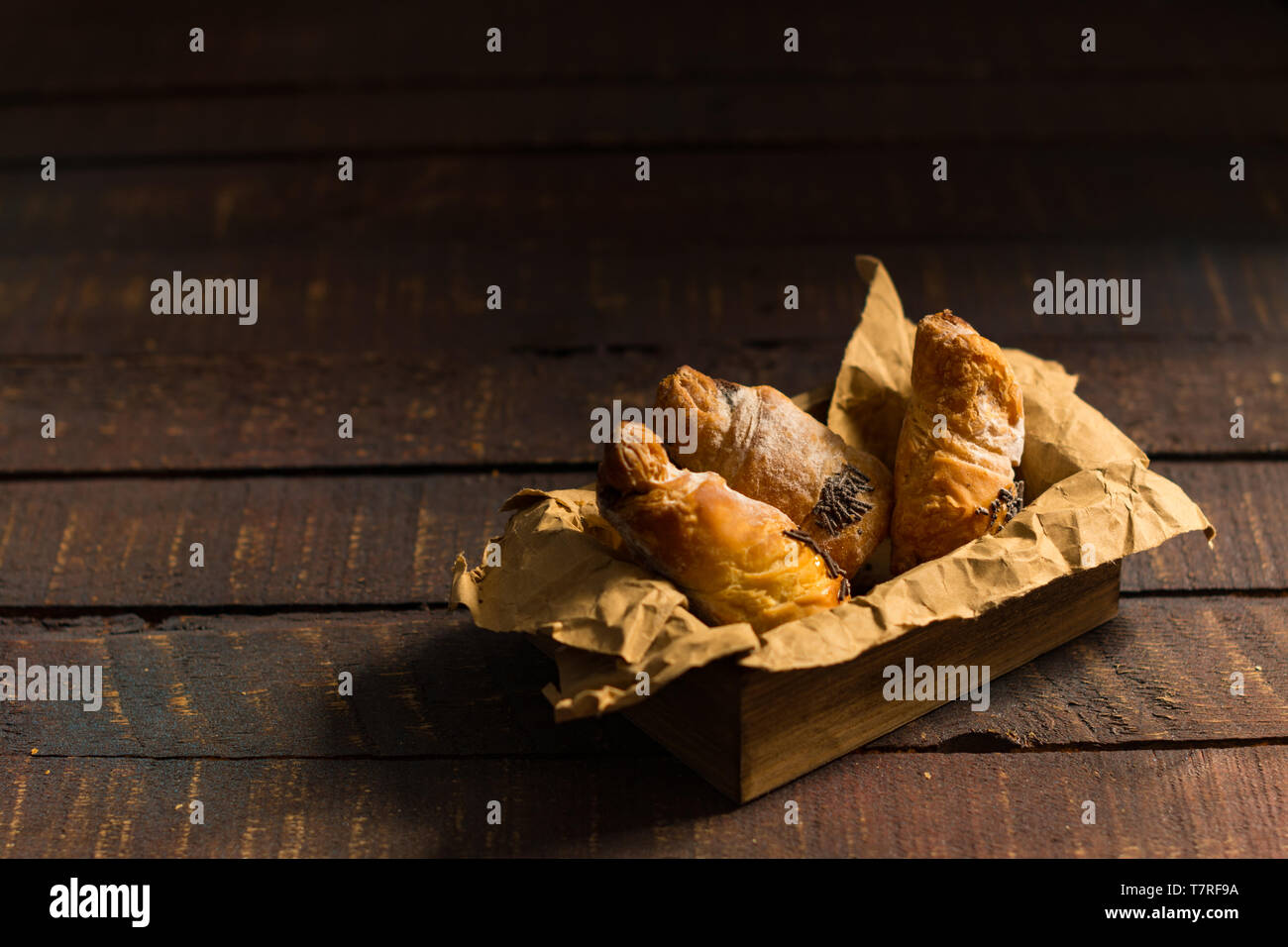 Croissants filled with chocolate in a paper into a box and a wooden ...