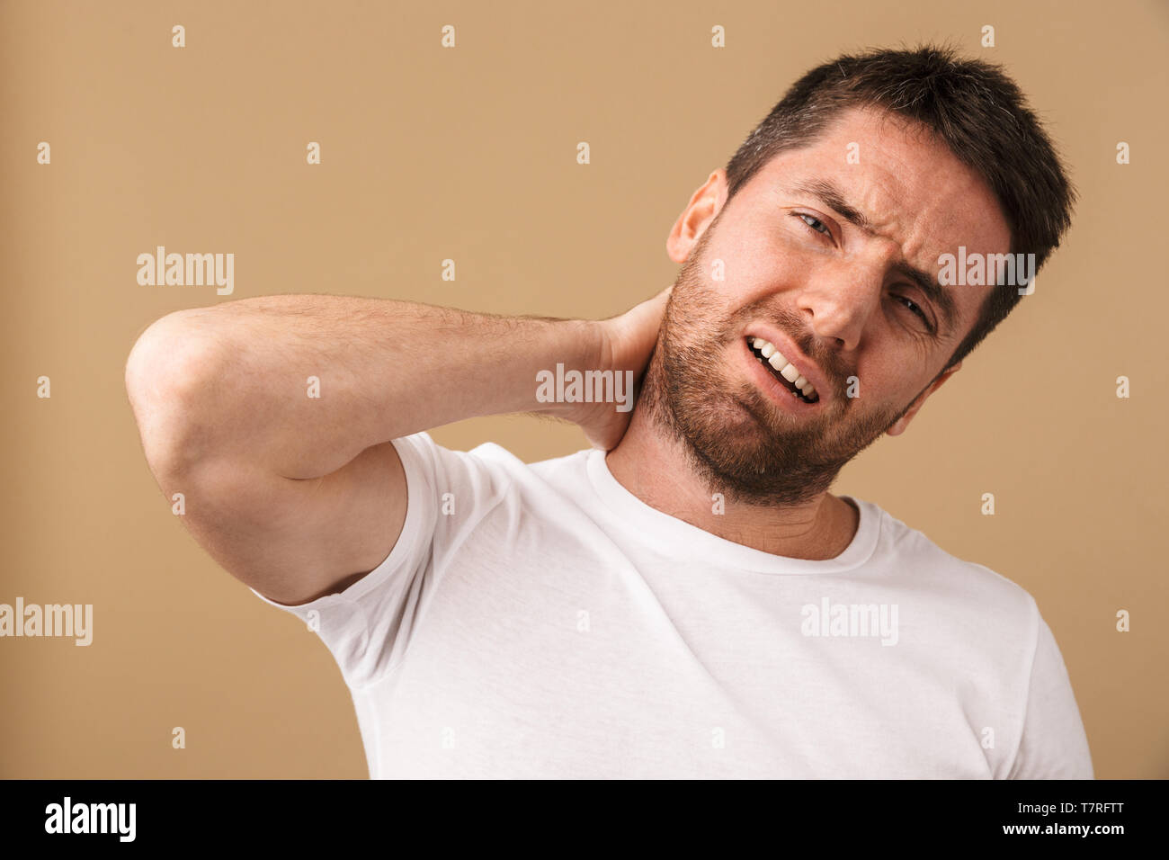 Portrait of a tired young man suffering from a headache isolated over ...