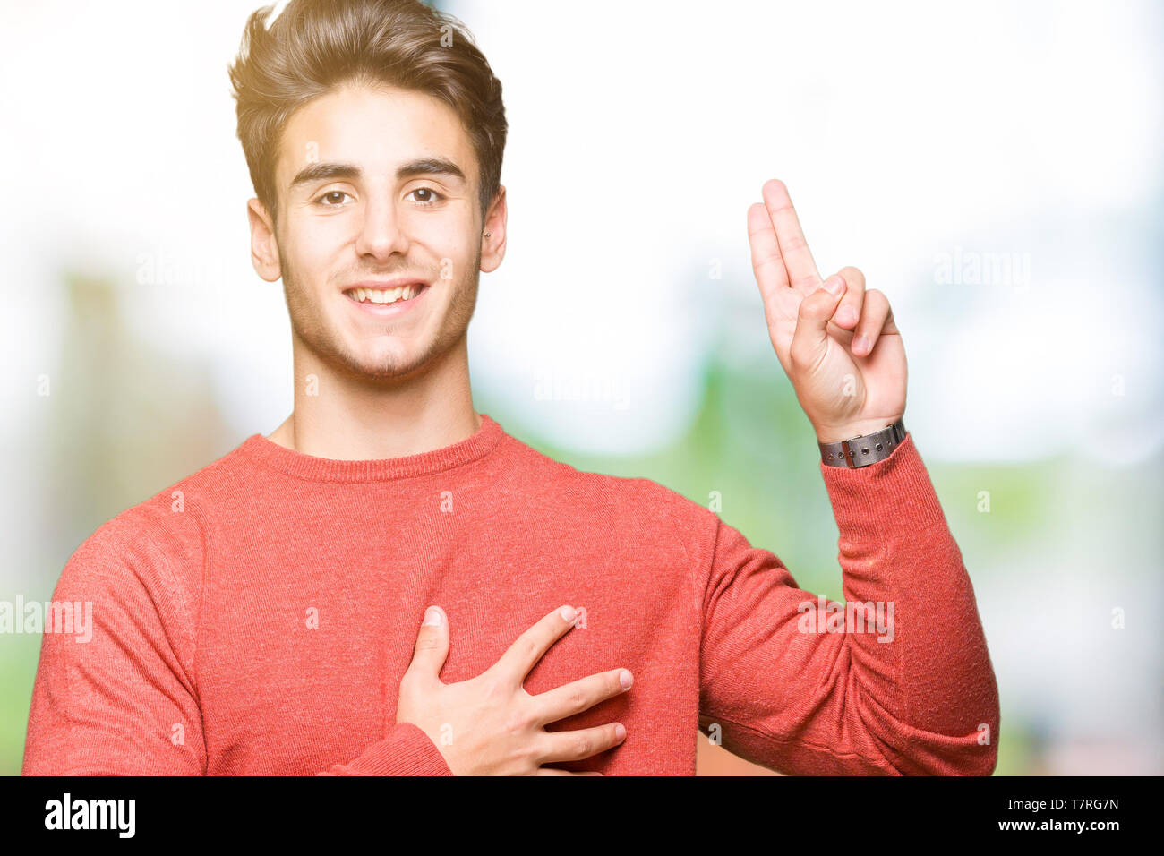 Young handsome man over isolated background Swearing with hand on chest ...