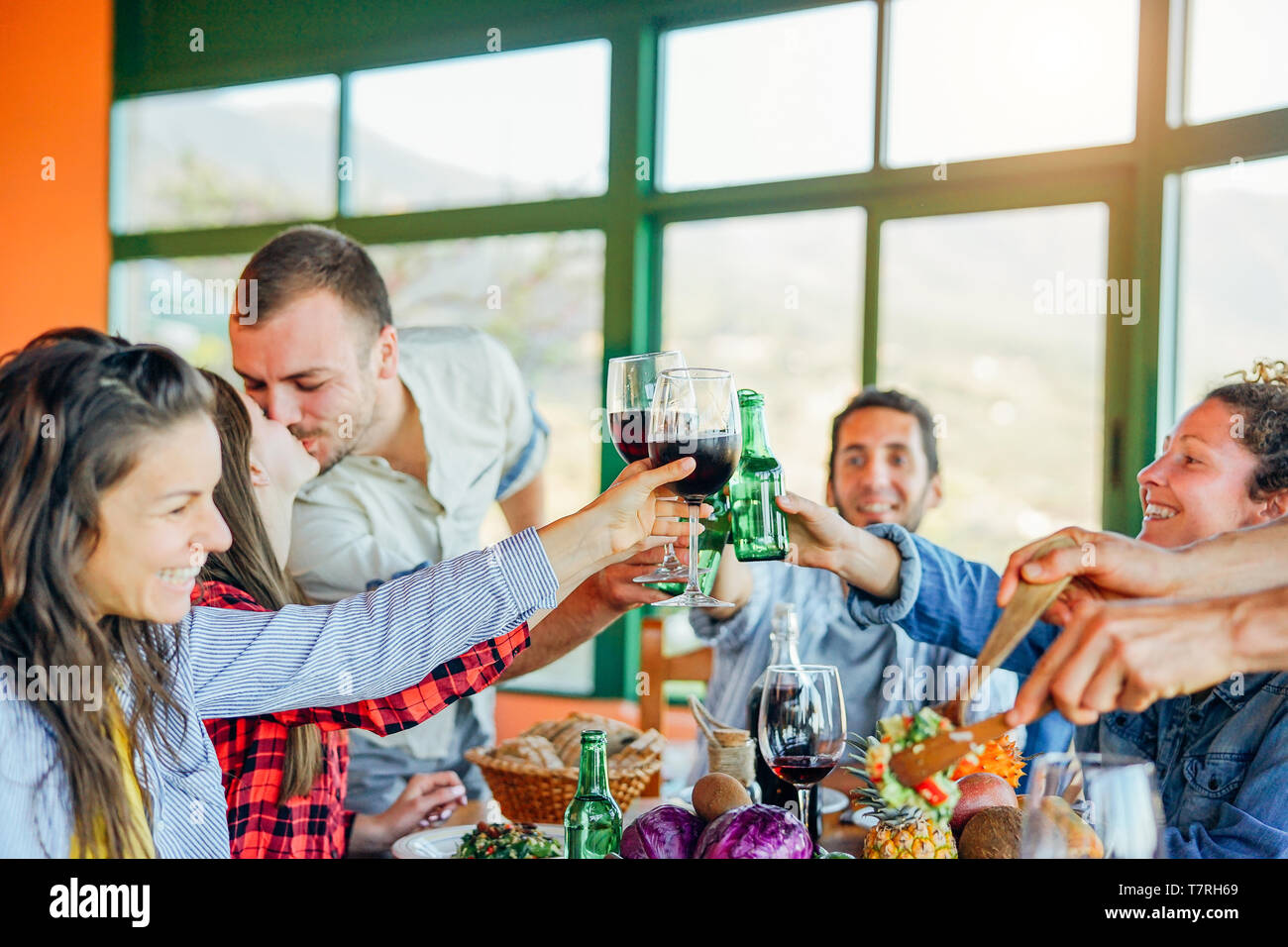 Happy friends cheering with glasses of red wine and beers at lunch ...