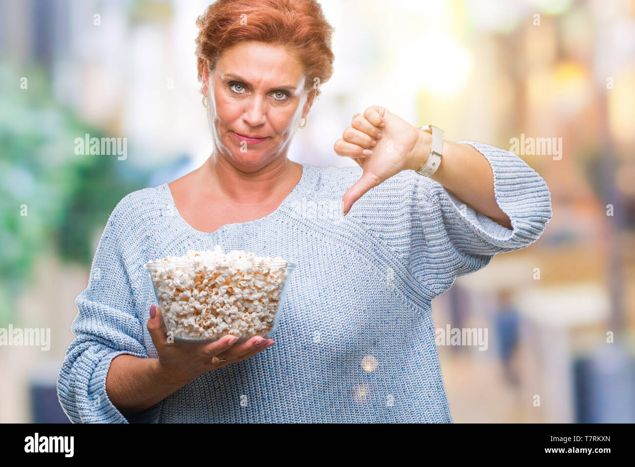Atrractive senior caucasian redhead woman eating popcorn over isolated ...