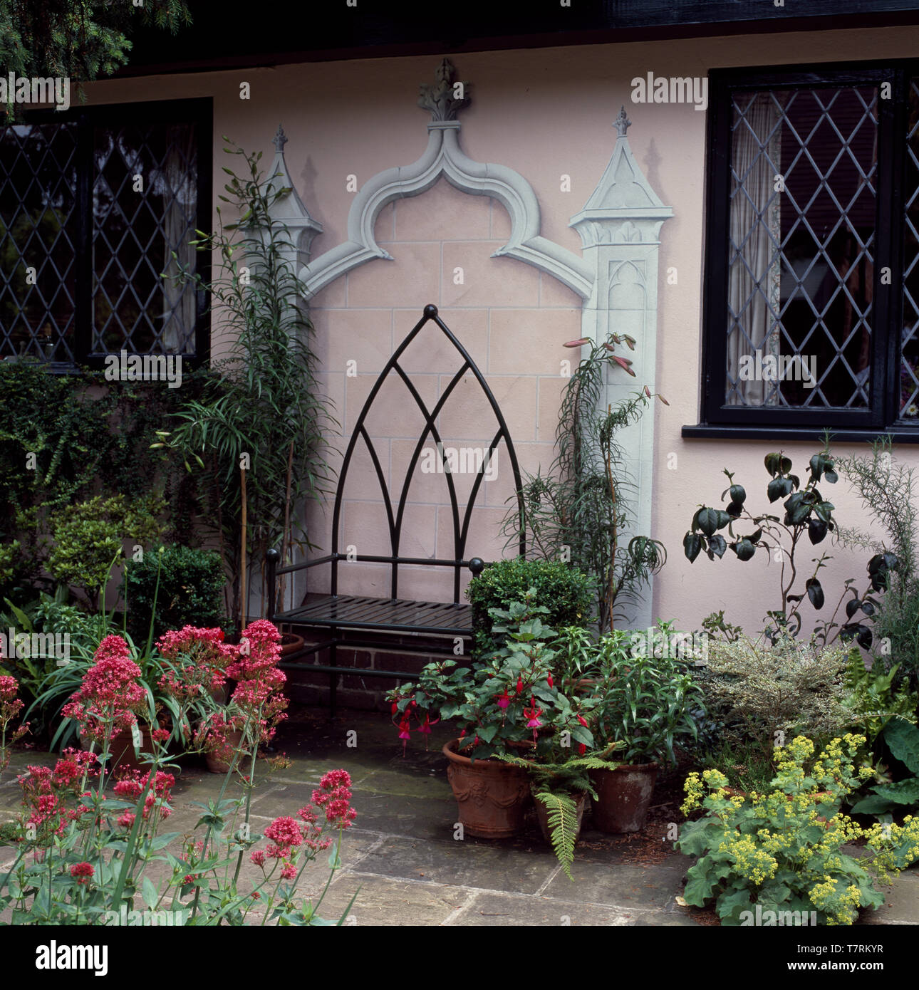 Metal Gothic style seat against wall painted with faux Gothic arch ...