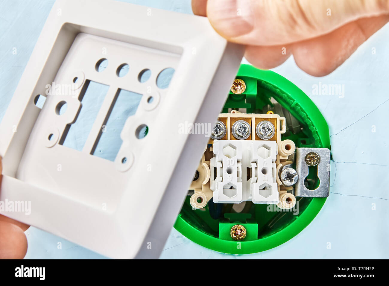 Worker is putting part of european push button on round electrical box ...