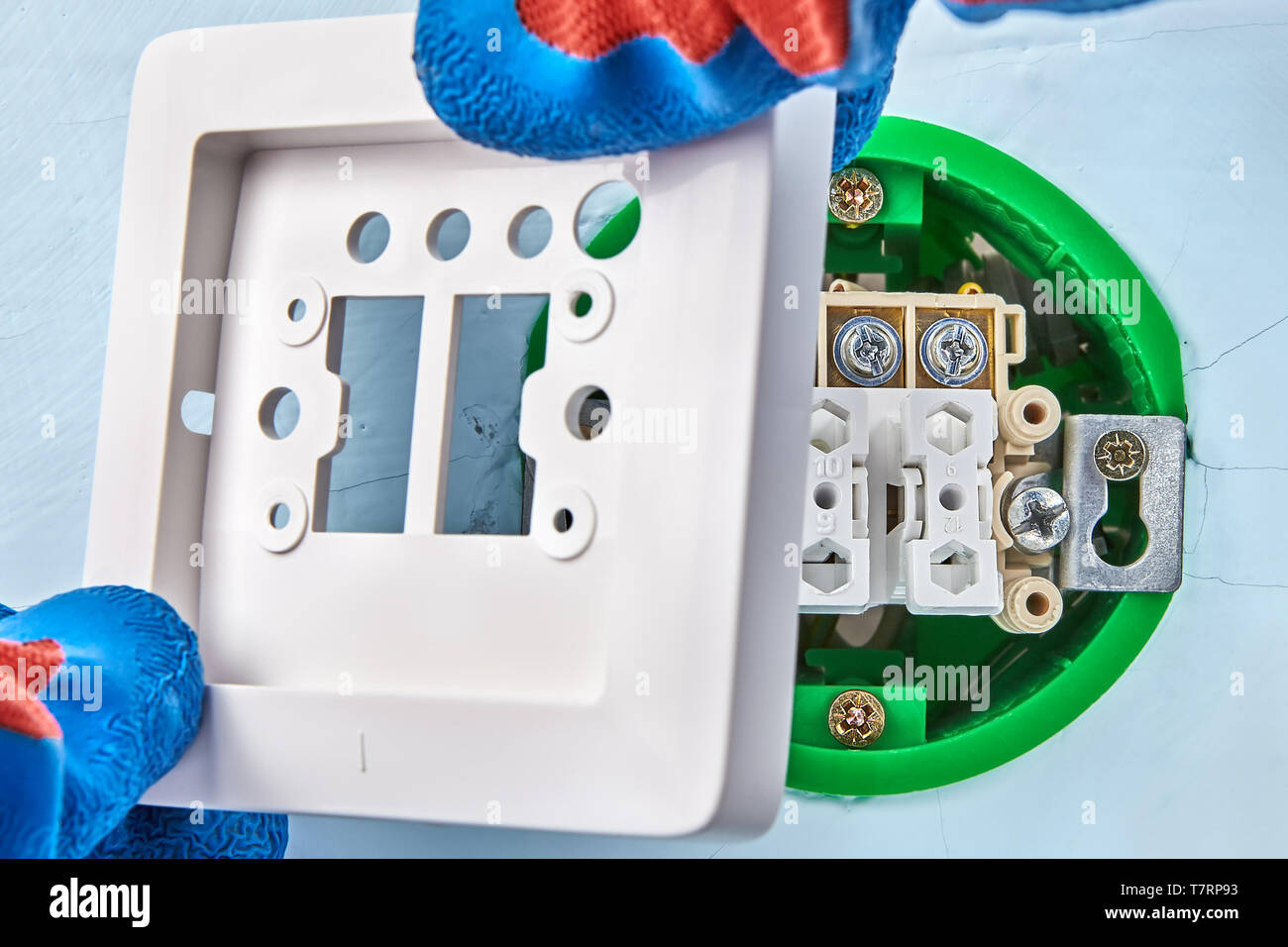 Worker in protective gloves is putting cover on round outlet box for ...