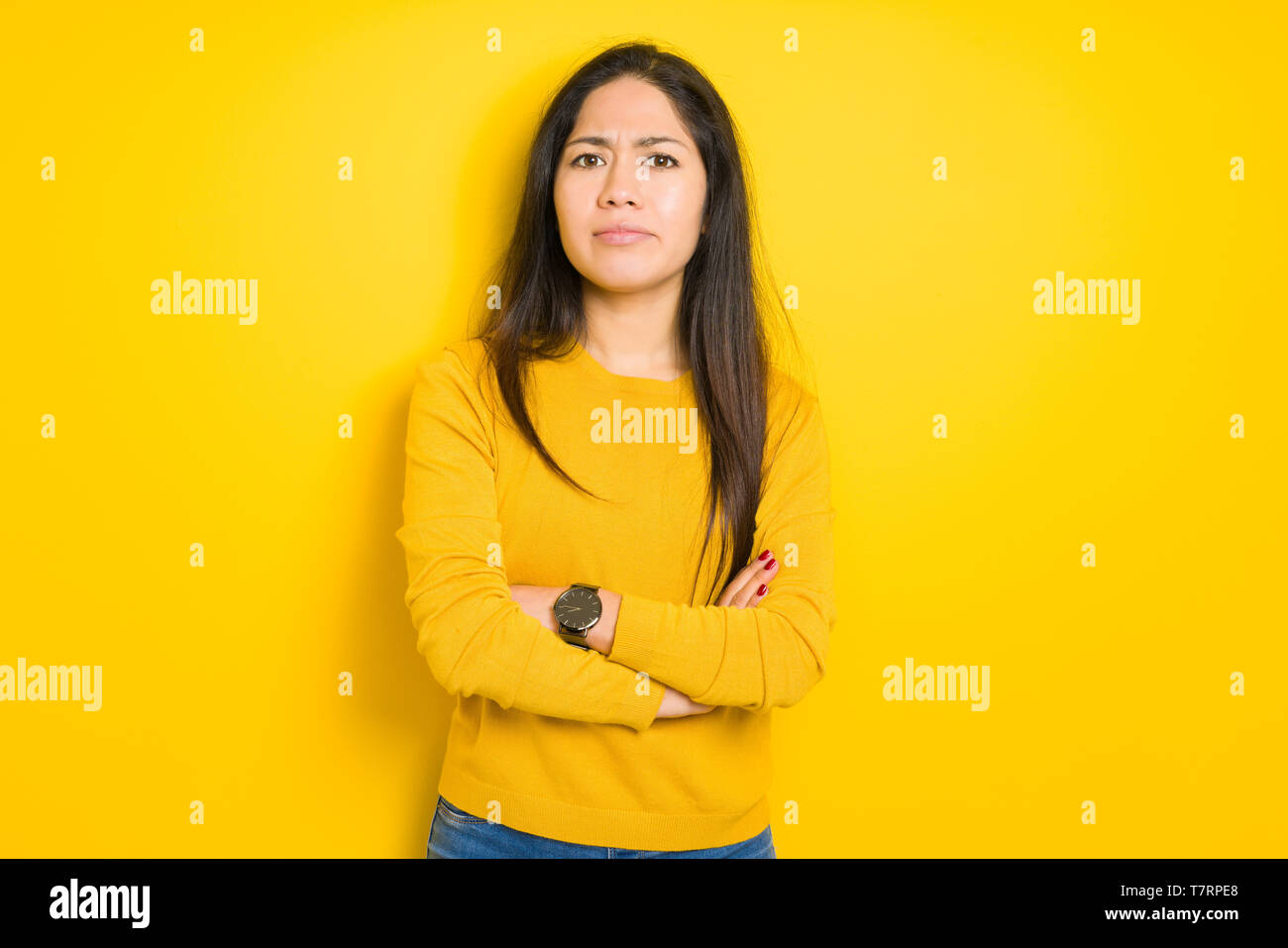 Beautiful brunette woman over yellow isolated background skeptic and ...
