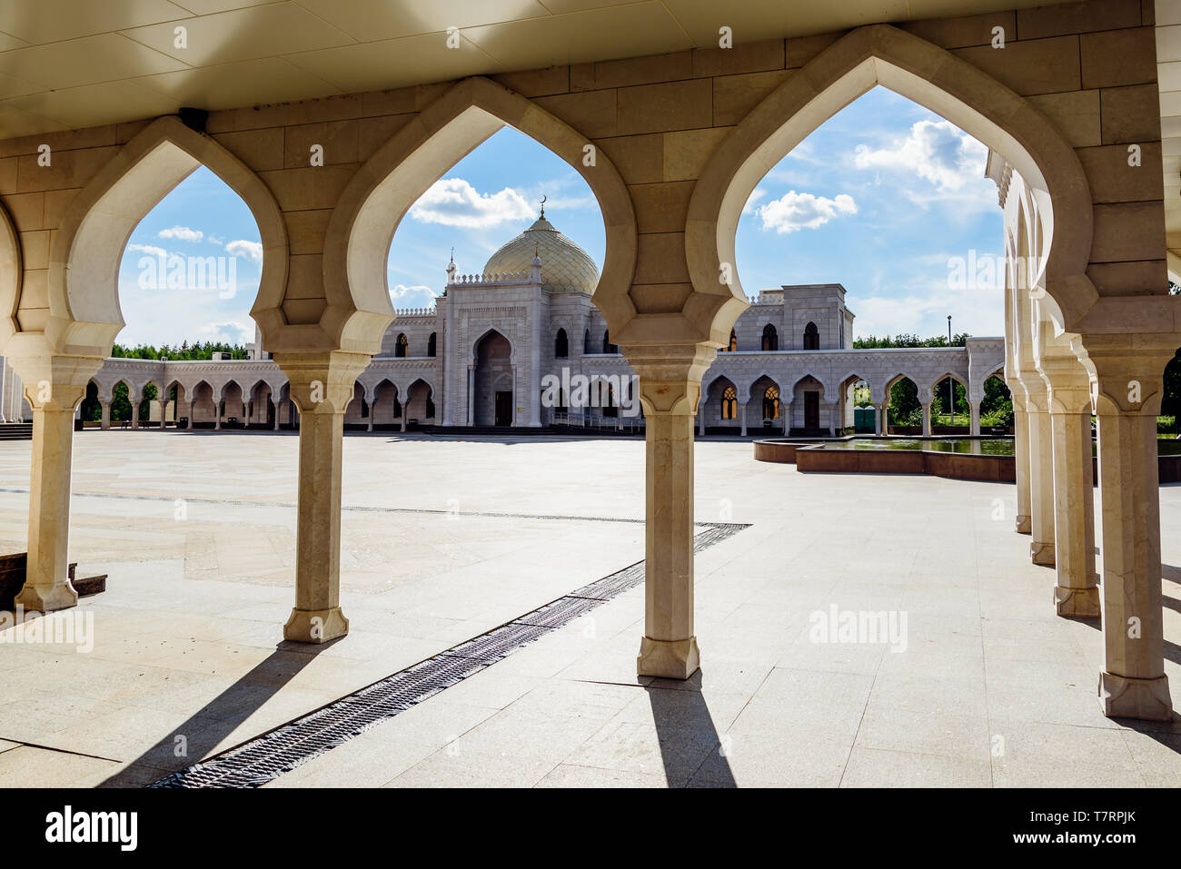 View of the white mosque in the sunset light through the Arches ...