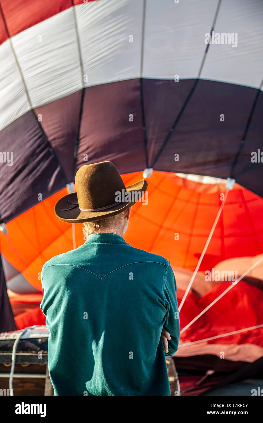 Man wearing hat looking at hot air balloon being inflated, White Sands ...