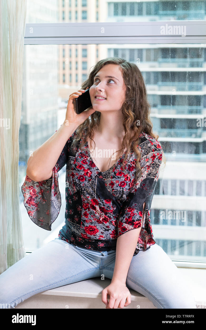 Closeup of young happy woman girl sitting at window in building talking ...