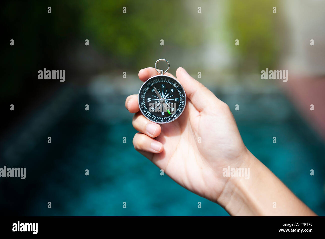 Hand holding compass in the swimming pool, searching direction with ...