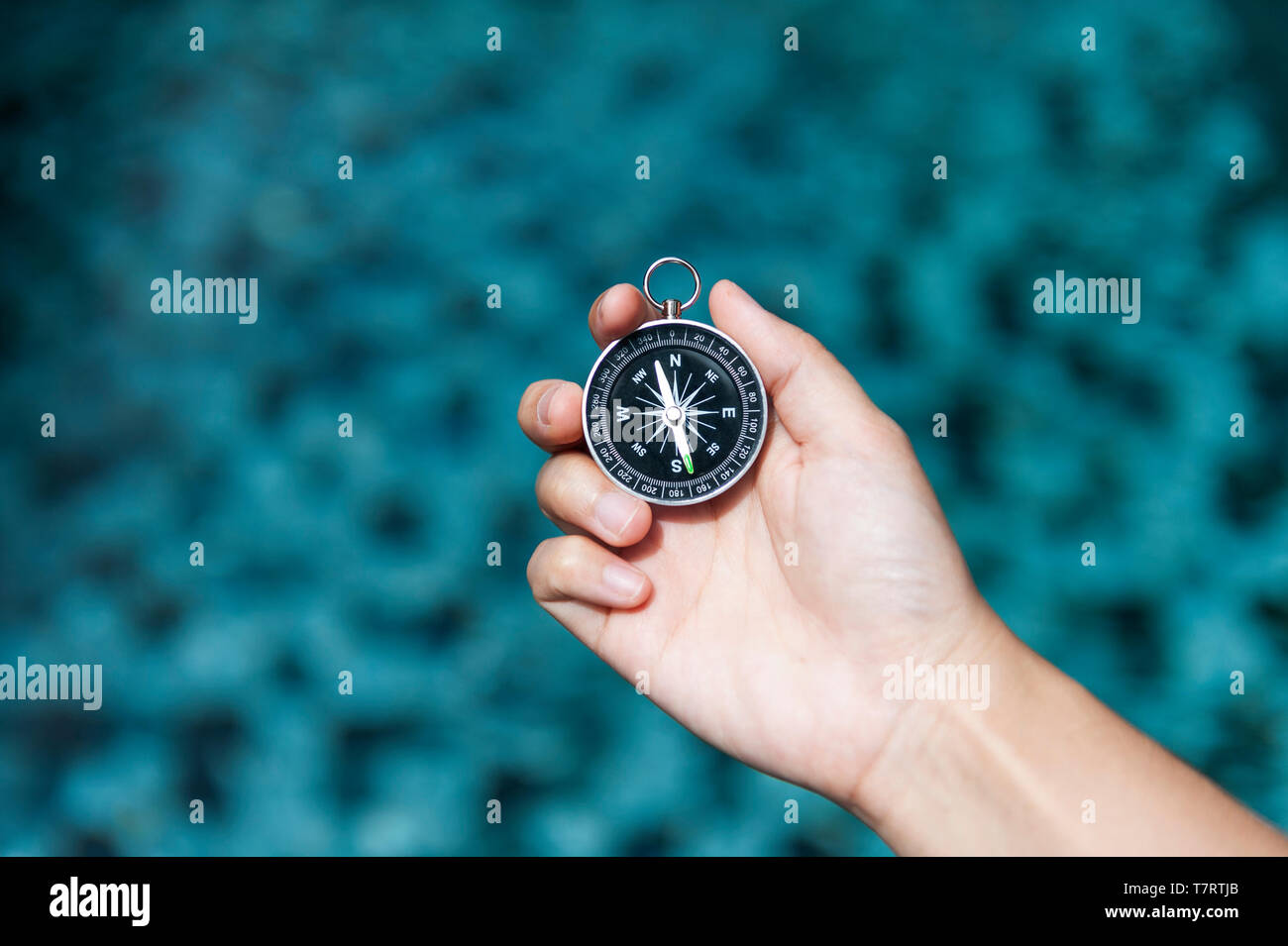 Hand holding compass in the swimming pool, searching direction with ...
