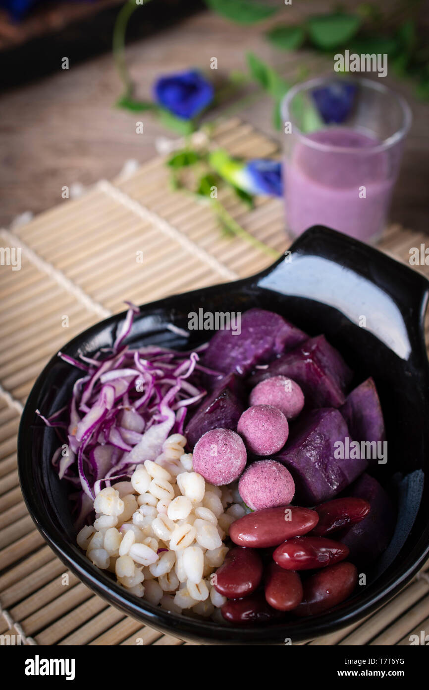 Purple vegetable salad in black bowl placed on wood sieve there are ...